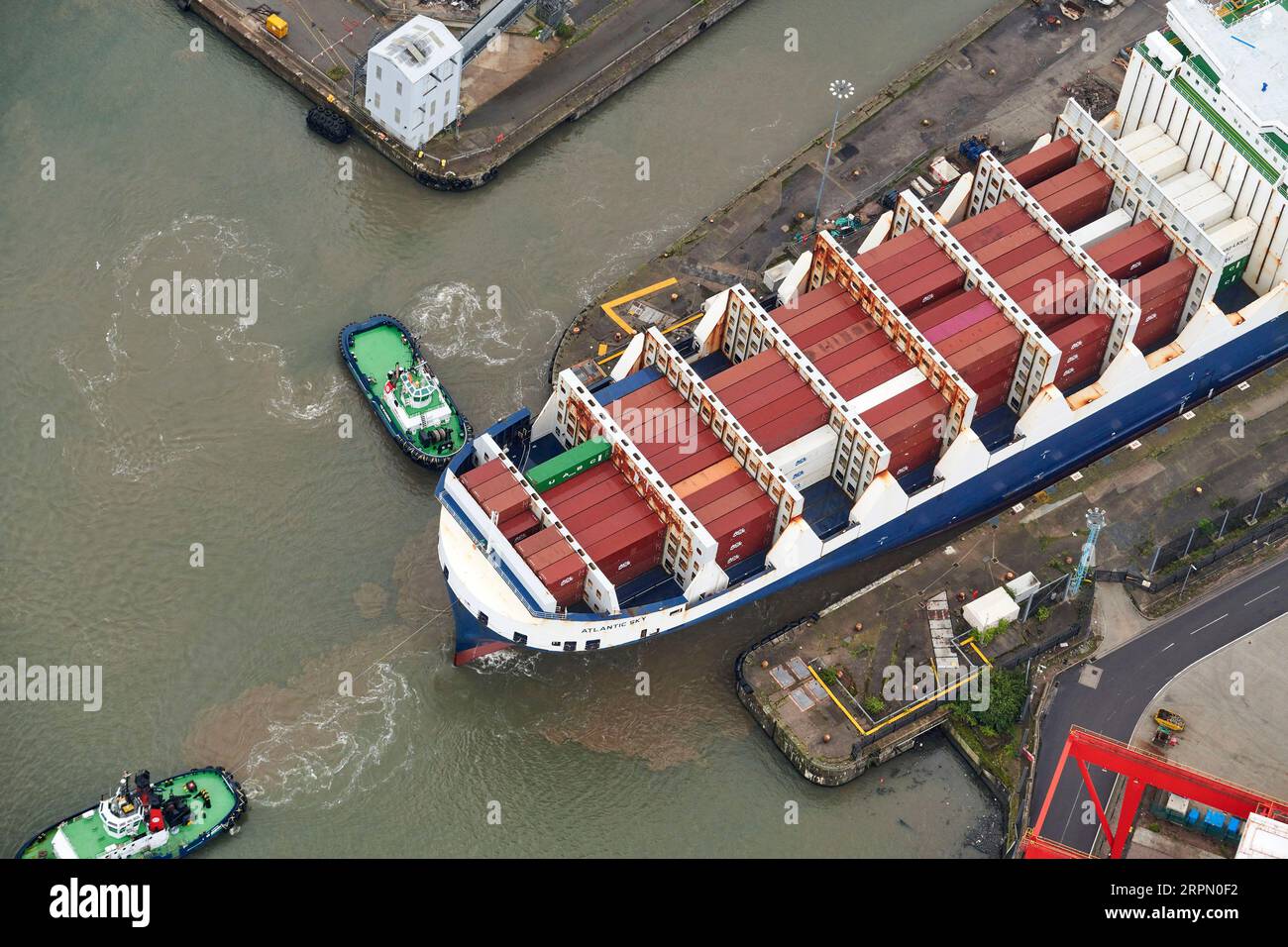 Tug boats guiding a container ship into Seaforth Docks, Liverpool ...