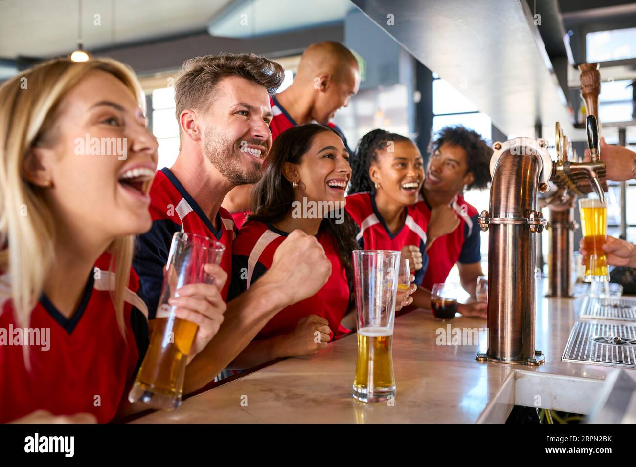 Multi-Cultural Group Of Friends Wearing Team Shirts In Sports Bar ...
