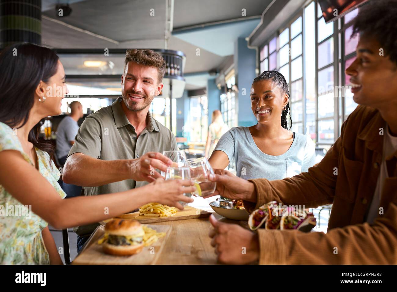 Multi-Cultural Group Of Friends Celebrating Meeting Up In Restaurant ...