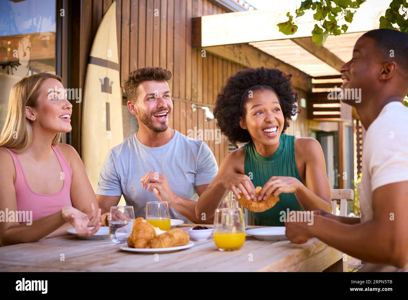 Group Of Smiling Multi-Cultural Friends Eating Breakfast Outdoors At ...