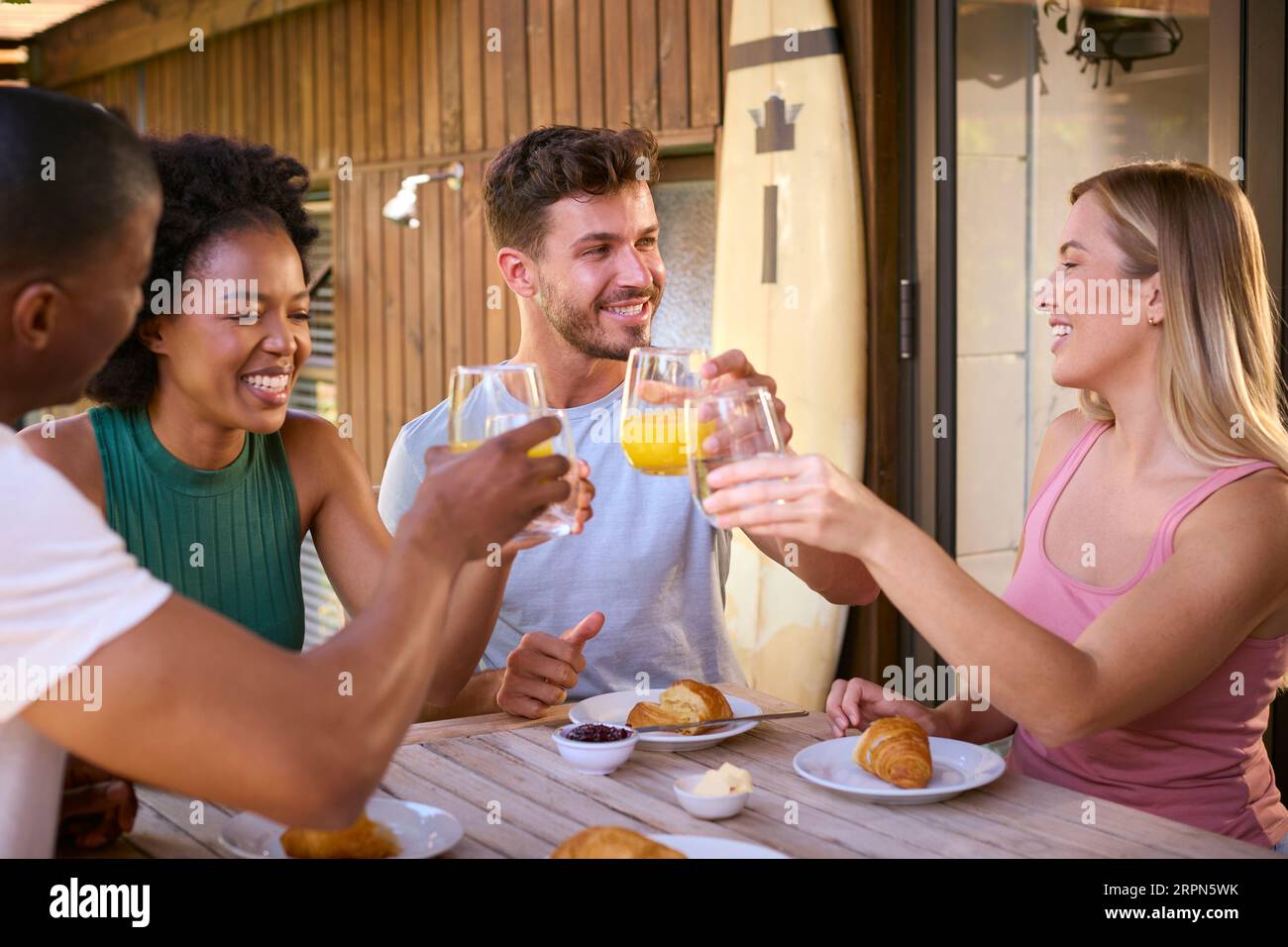 Group Of Smiling Multi-Cultural Friends Eating Breakfast Outdoors At ...