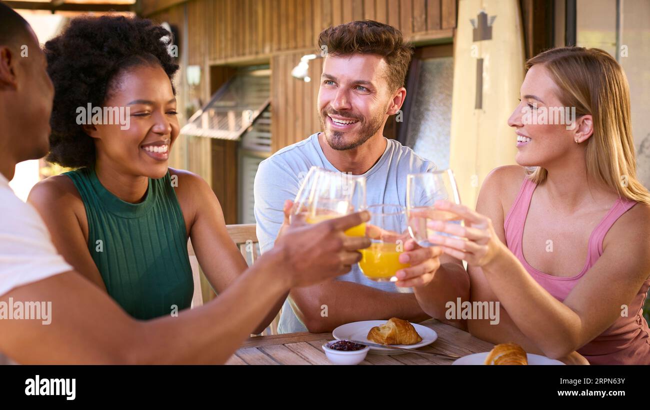 Group Of Smiling Multi-Cultural Friends Eating Breakfast Outdoors At ...