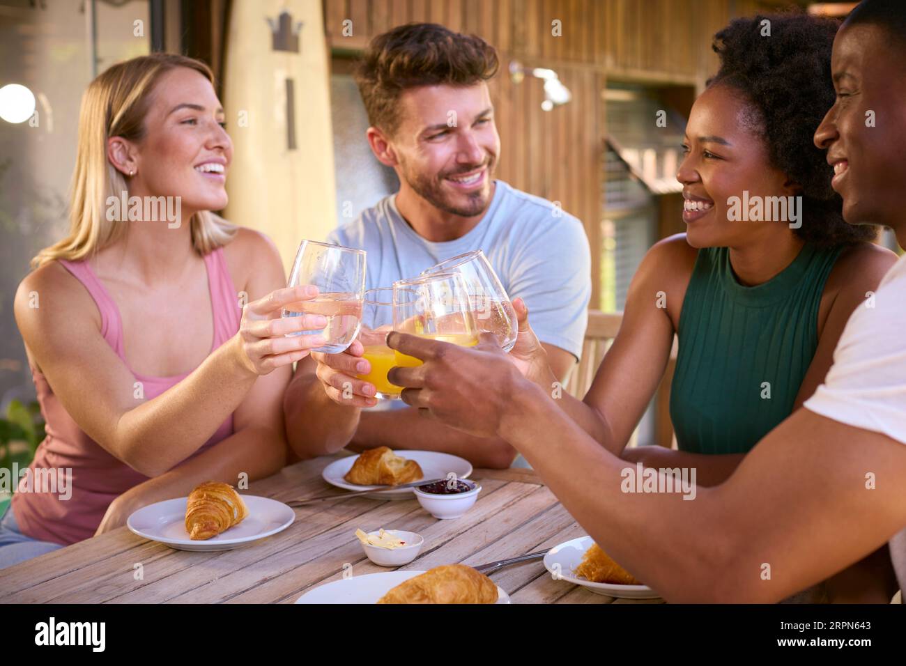 Group Of Smiling Multi-Cultural Friends Eating Breakfast Outdoors At ...