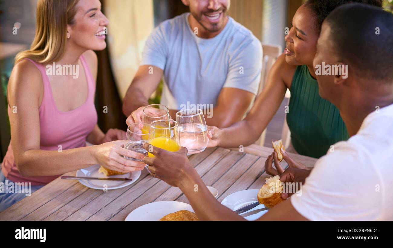 Group Of Smiling Multi-Cultural Friends Eating Breakfast Outdoors At ...