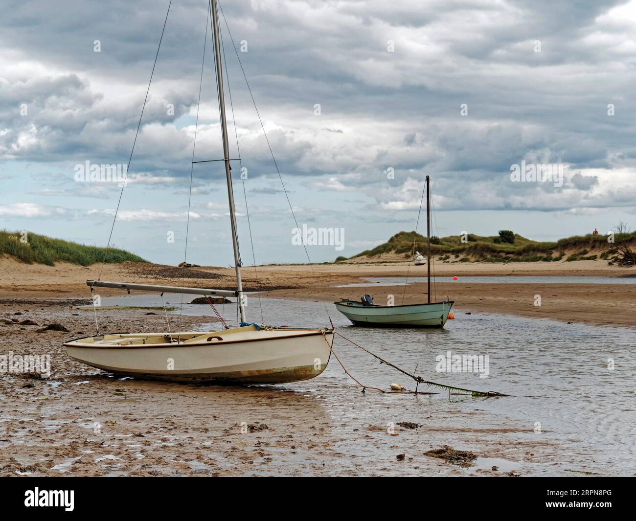 Small sailing boats aground on the sandy mud of the sheltered harbour ...