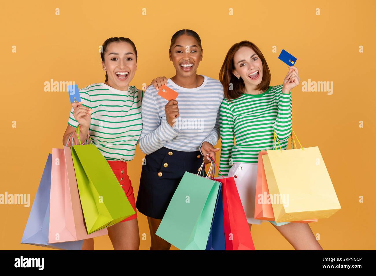 Three attractive young multiethnic ladies shopping together, using ...