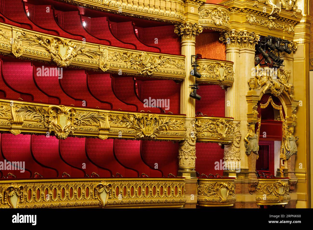A opera theatre featuring an ornate stage with a patterned red carpet ...