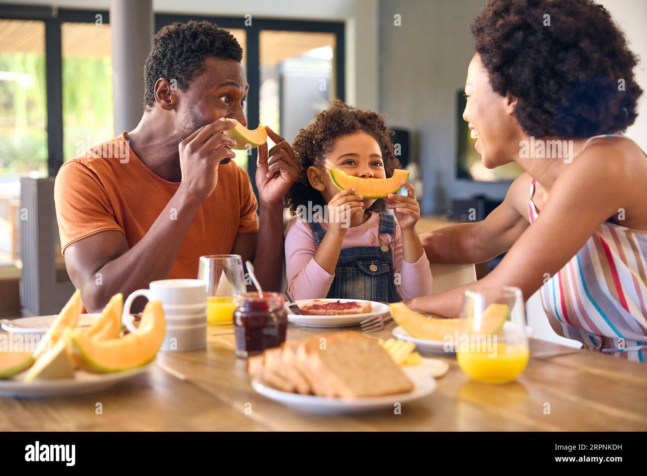 Family Shot With Parents And Daughter At Home Making Funny Faces With ...