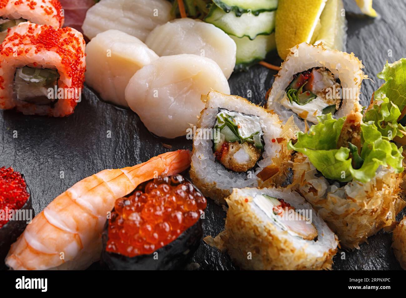 Sushi set of rolls with scallops and vegetables, on black stone Stock ...