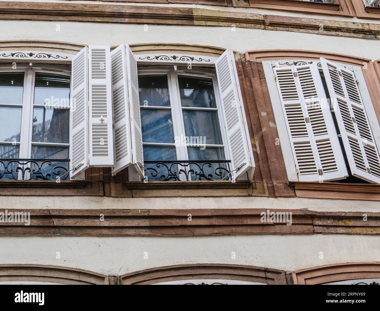 Colorful French building with ornate balconies, open sunshades, and ...