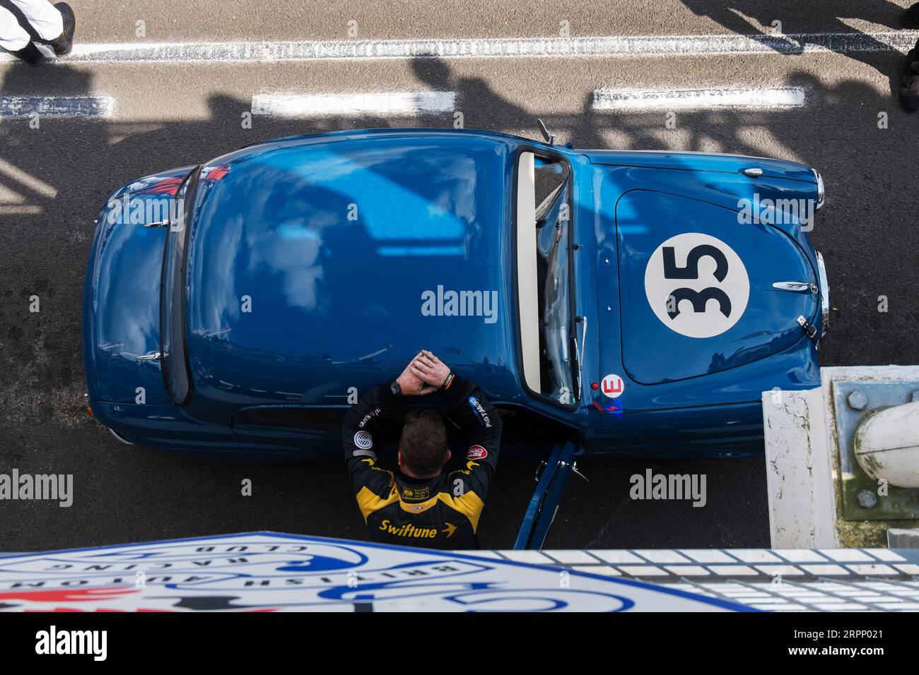 The driver leaning on a 1950s Austin A35 in the pit lane at a test day ...