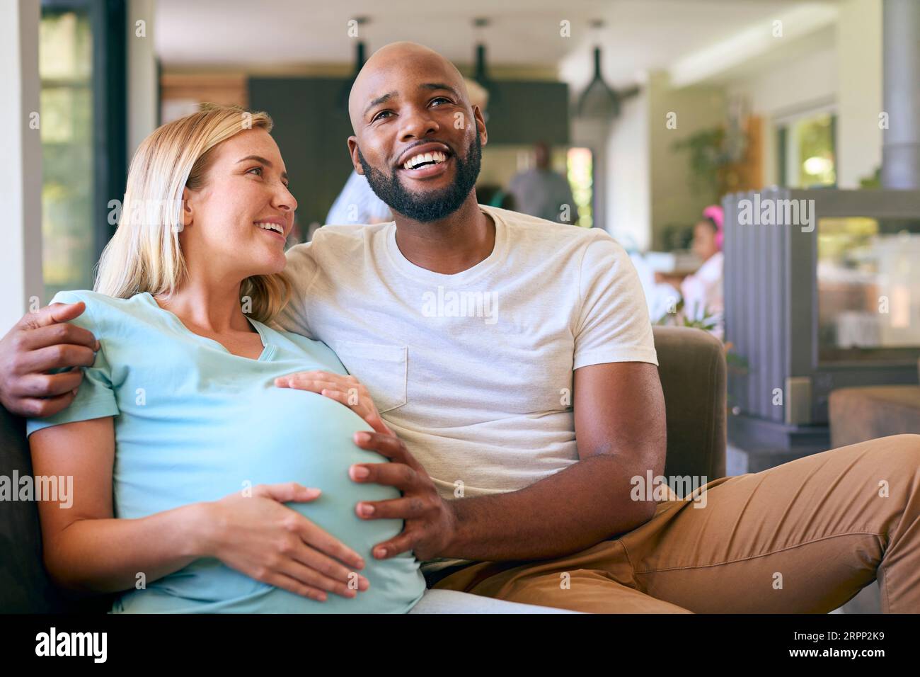 Loving Multi-Racial Couple With Pregnant Woman On Sofa At Home With ...