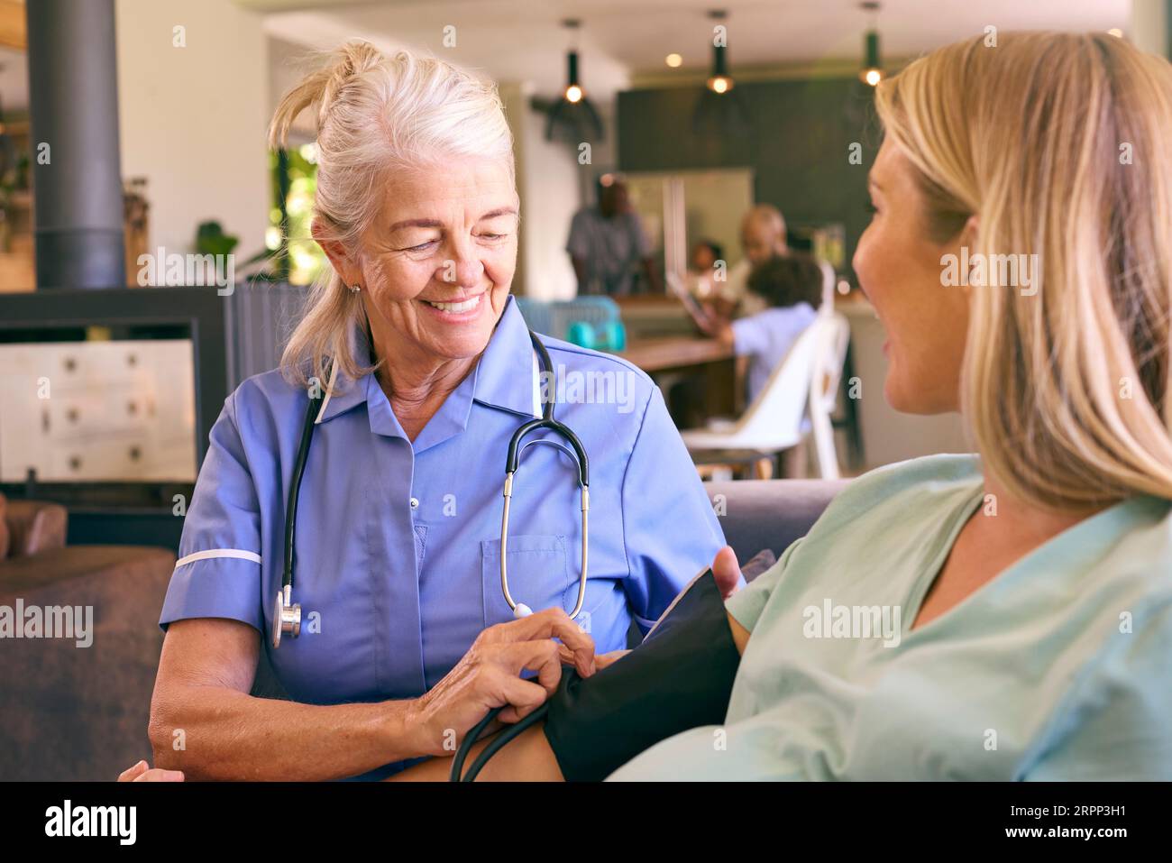Senior Midwife Visiting Pregnant Woman At Home Taking Blood Pressure ...