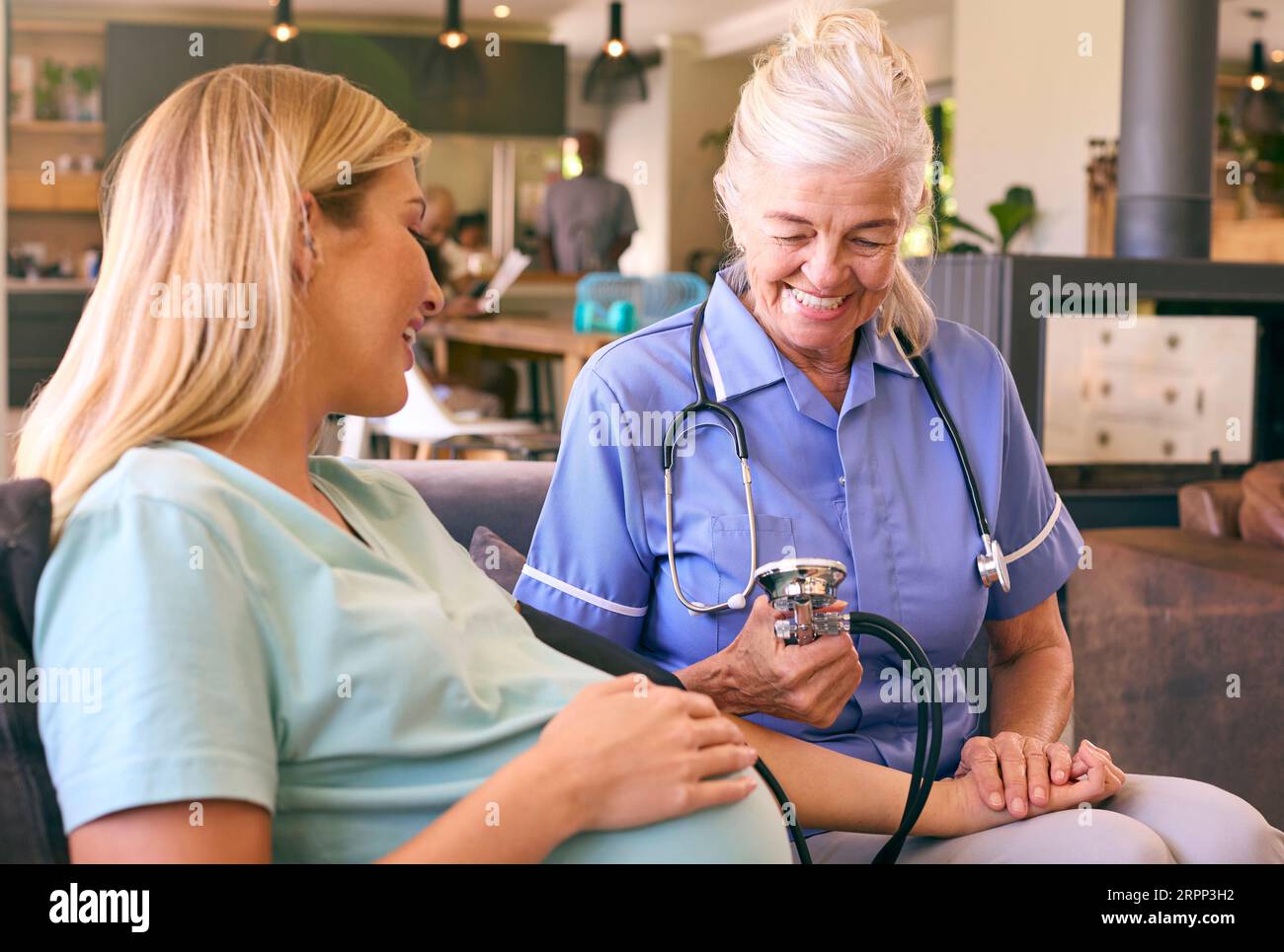 Senior Midwife Visiting Pregnant Woman At Home Taking Blood Pressure ...