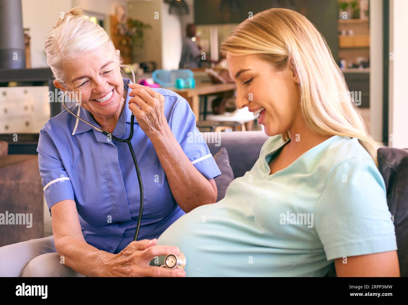 Senior Midwife With Stethoscope Visiting Pregnant Woman At Home With ...
