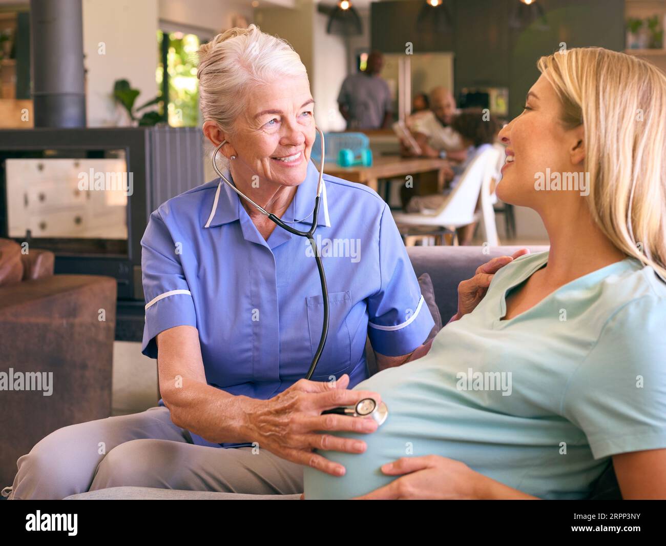 Senior Midwife With Stethoscope Visiting Pregnant Woman At Home With ...