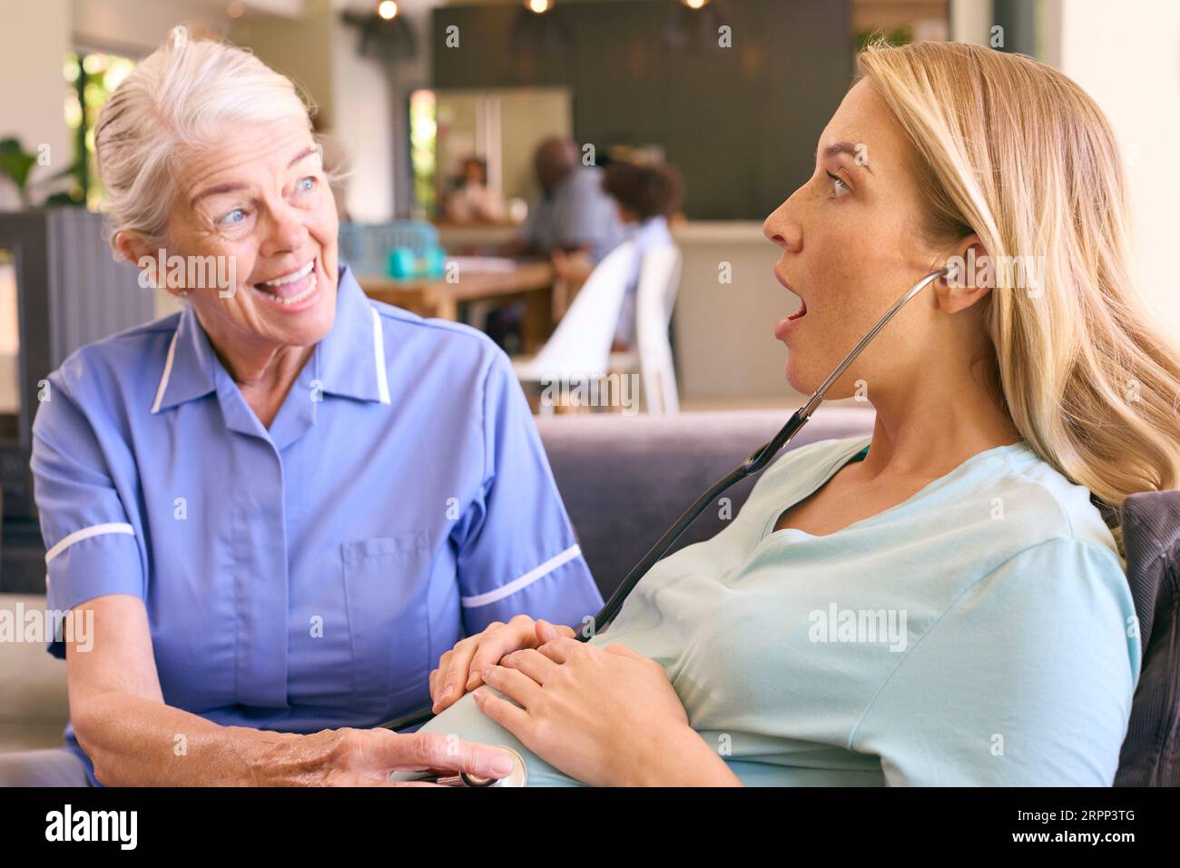 Senior Midwife With Stethoscope Visiting Pregnant Woman At Home With ...