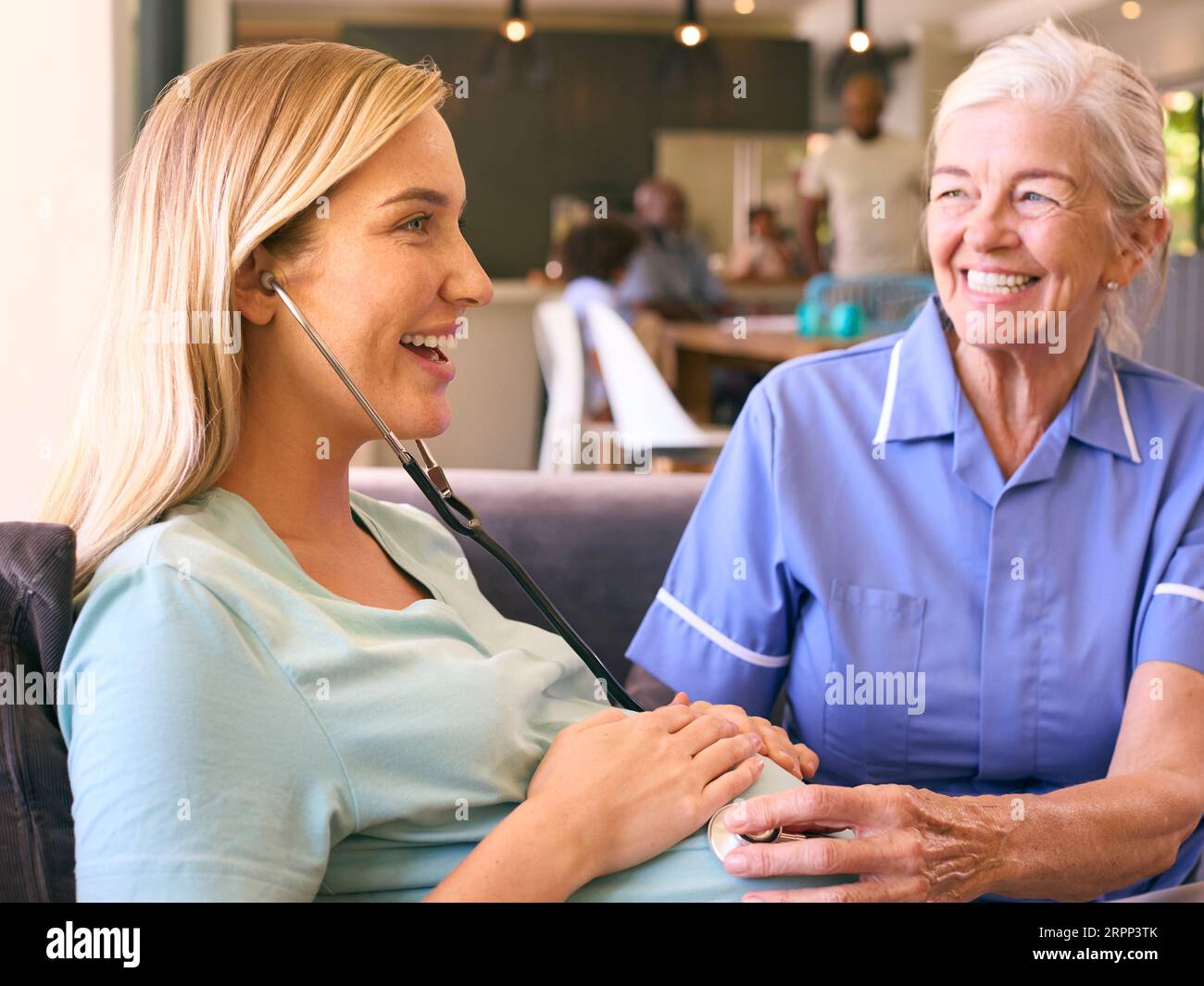 Senior Midwife With Stethoscope Visiting Pregnant Woman At Home With ...
