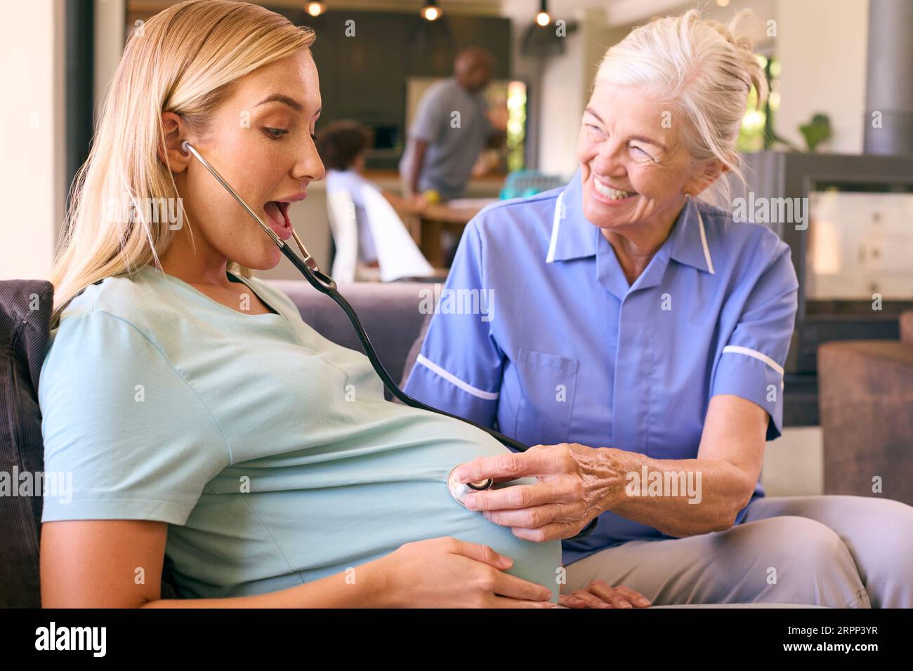 Senior Midwife With Stethoscope Visiting Pregnant Woman At Home With ...