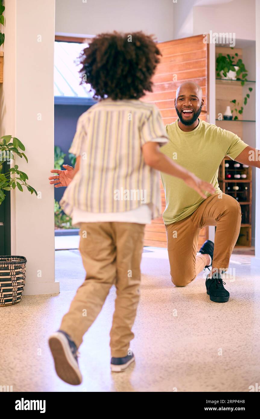 Son Greeting Father Returning Home With Luggage From Trip Away Stock ...