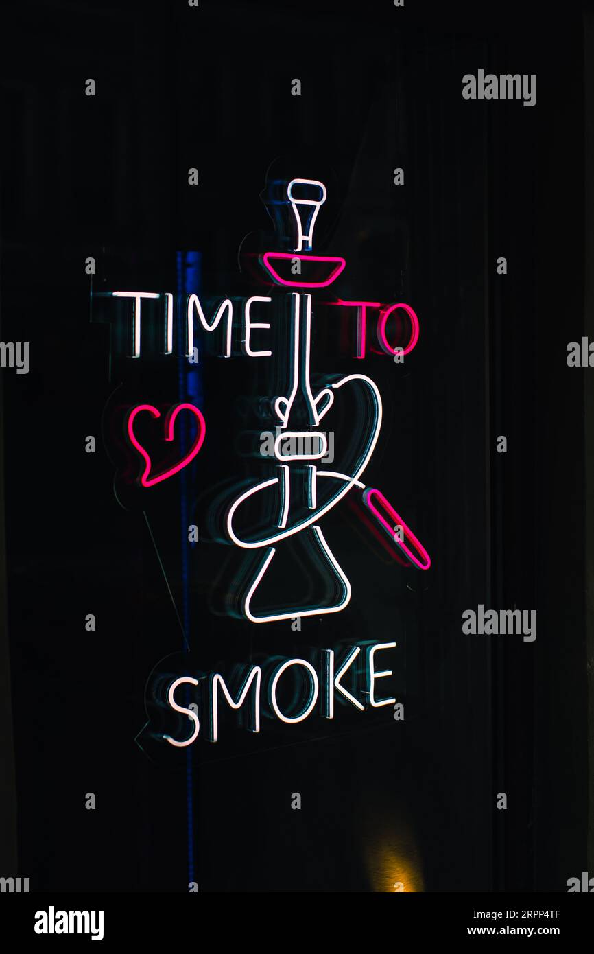 Neon sign on a black background, white pink text Time to smoke and ...