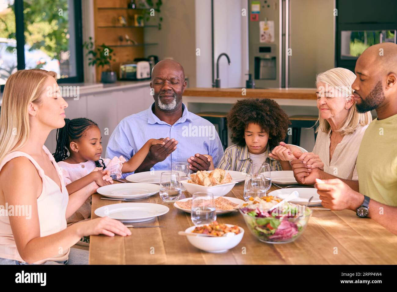 Multi-Generation Family Holding Hands And Saying Prayer Before Meal At ...