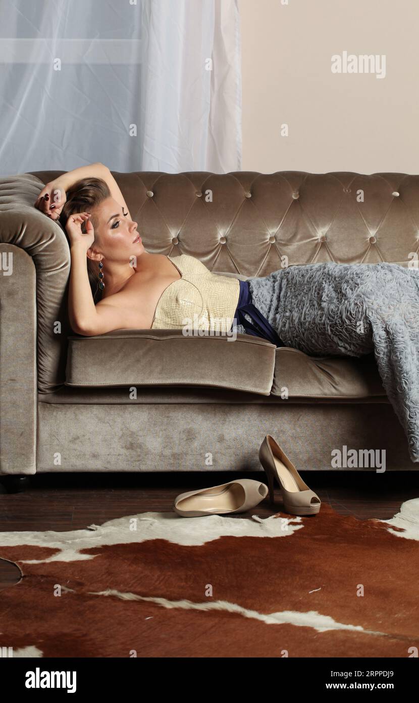 Perfect young model woman in glamorous dress relaxing on sofa, fashion ...