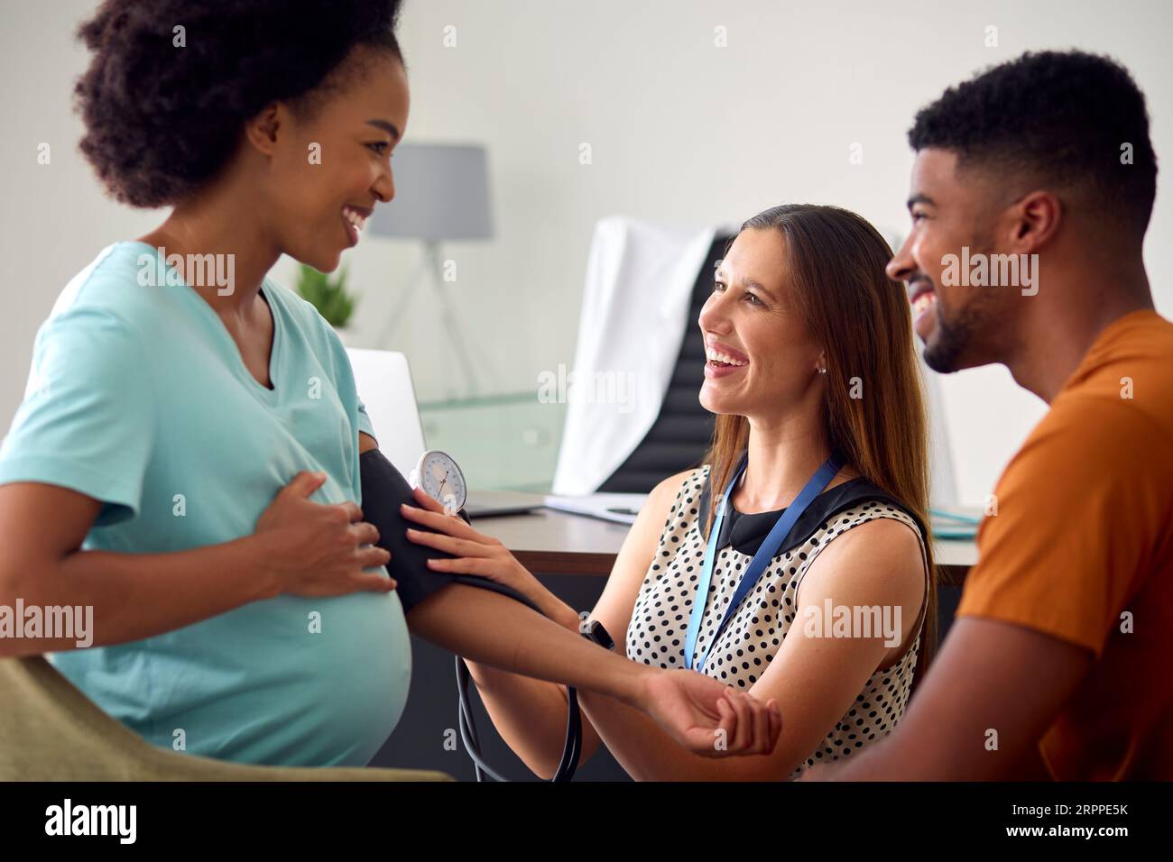 Pregnant Couple At Appointment With Female Doctor Or GP Taking Blood ...