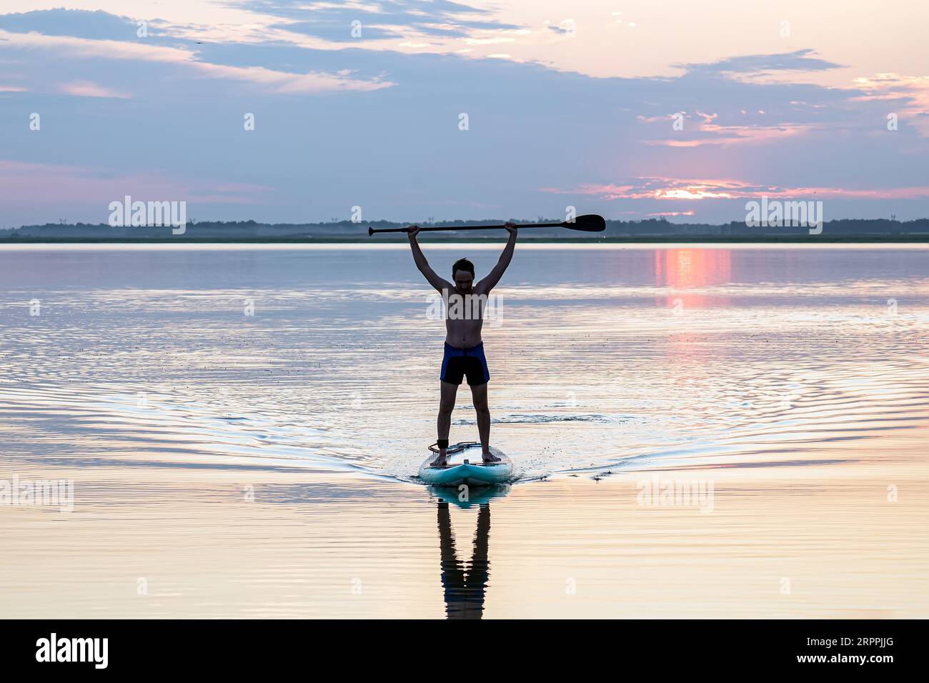 side view silhouette of alone male paddle boarder in sunset. Paddle ...