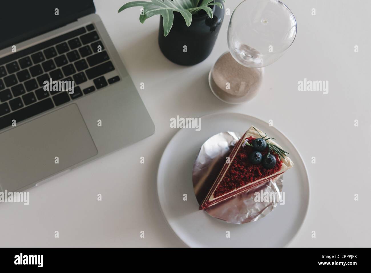 Top view of a delicious cake next to a sleek laptop computer on a white ...