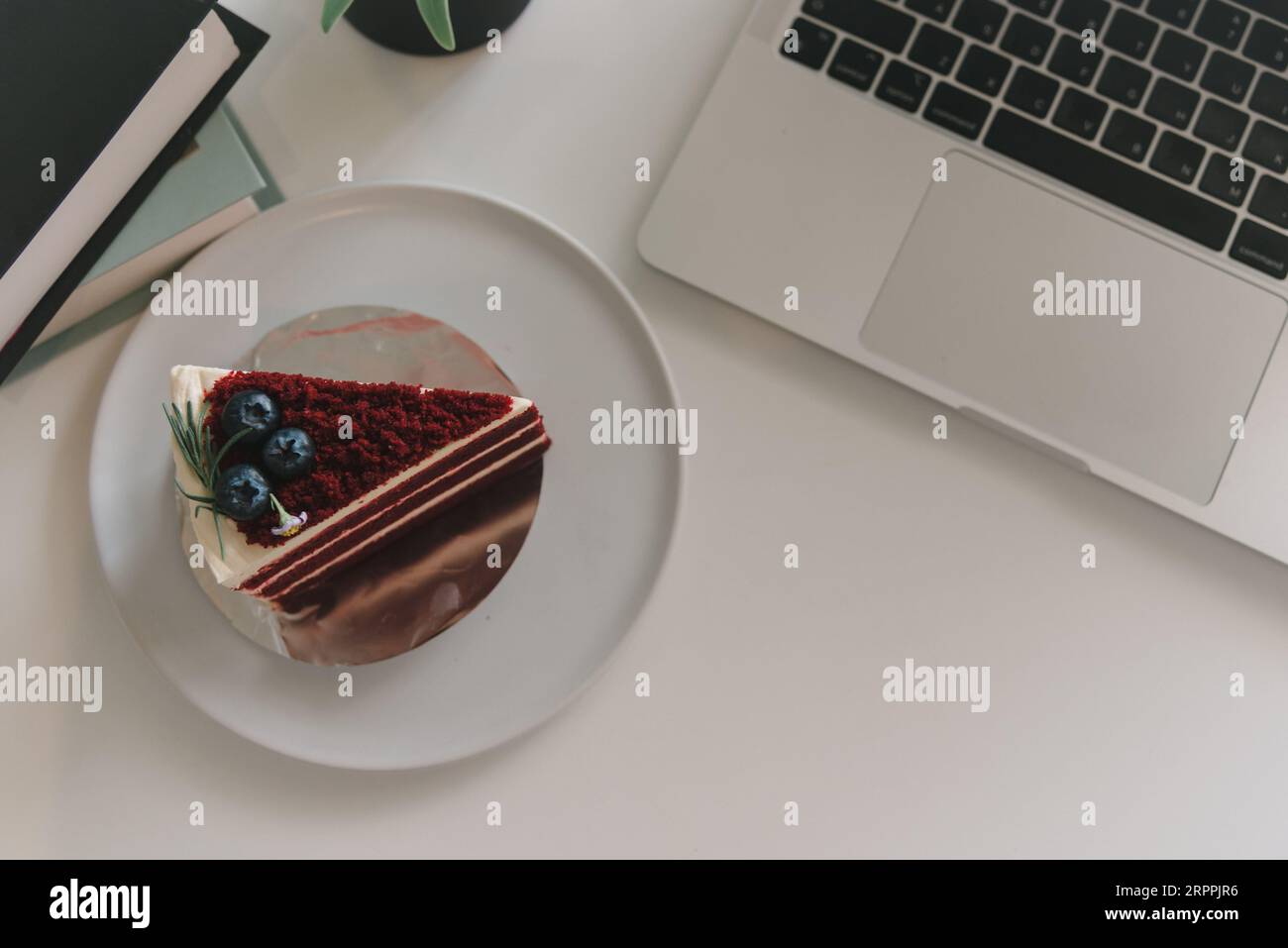 Top view of a delicious cake next to a sleek laptop computer on a white ...