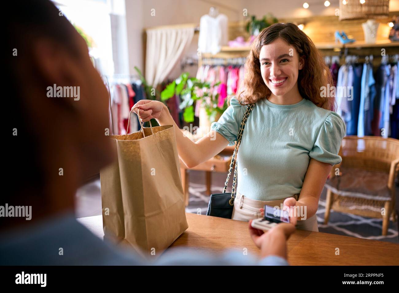 Female Customer In Fashion Store Paying For Clothes With Contactless ...