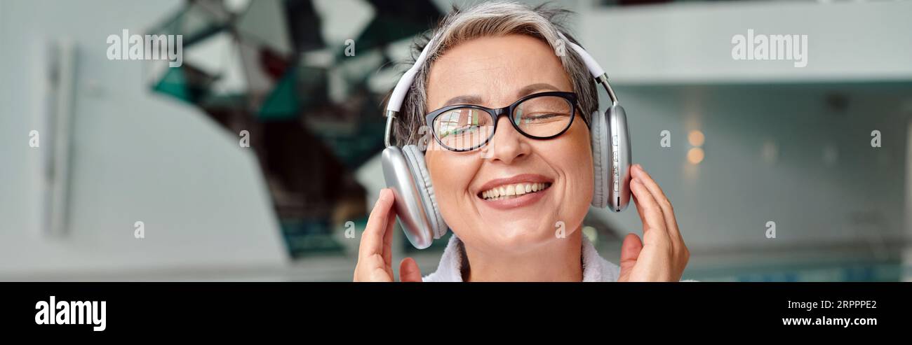 happy middle aged woman in glasses listening music in wireless ...