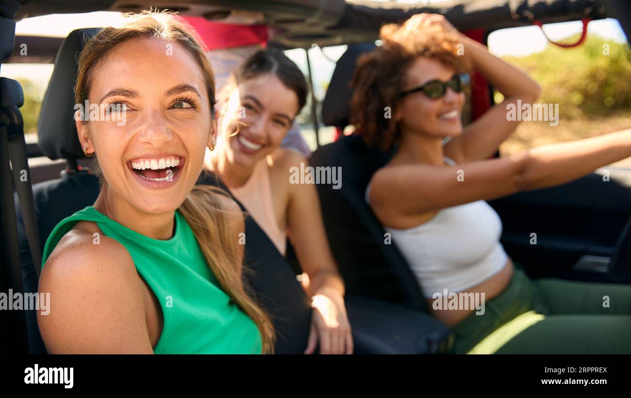 Group Of Laughing Female Friends Having Fun In Open Top Car On Road ...