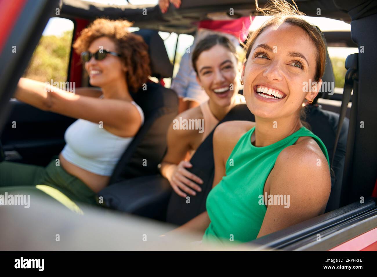 Group Of Laughing Female Friends Having Fun In Open Top Car On Road ...