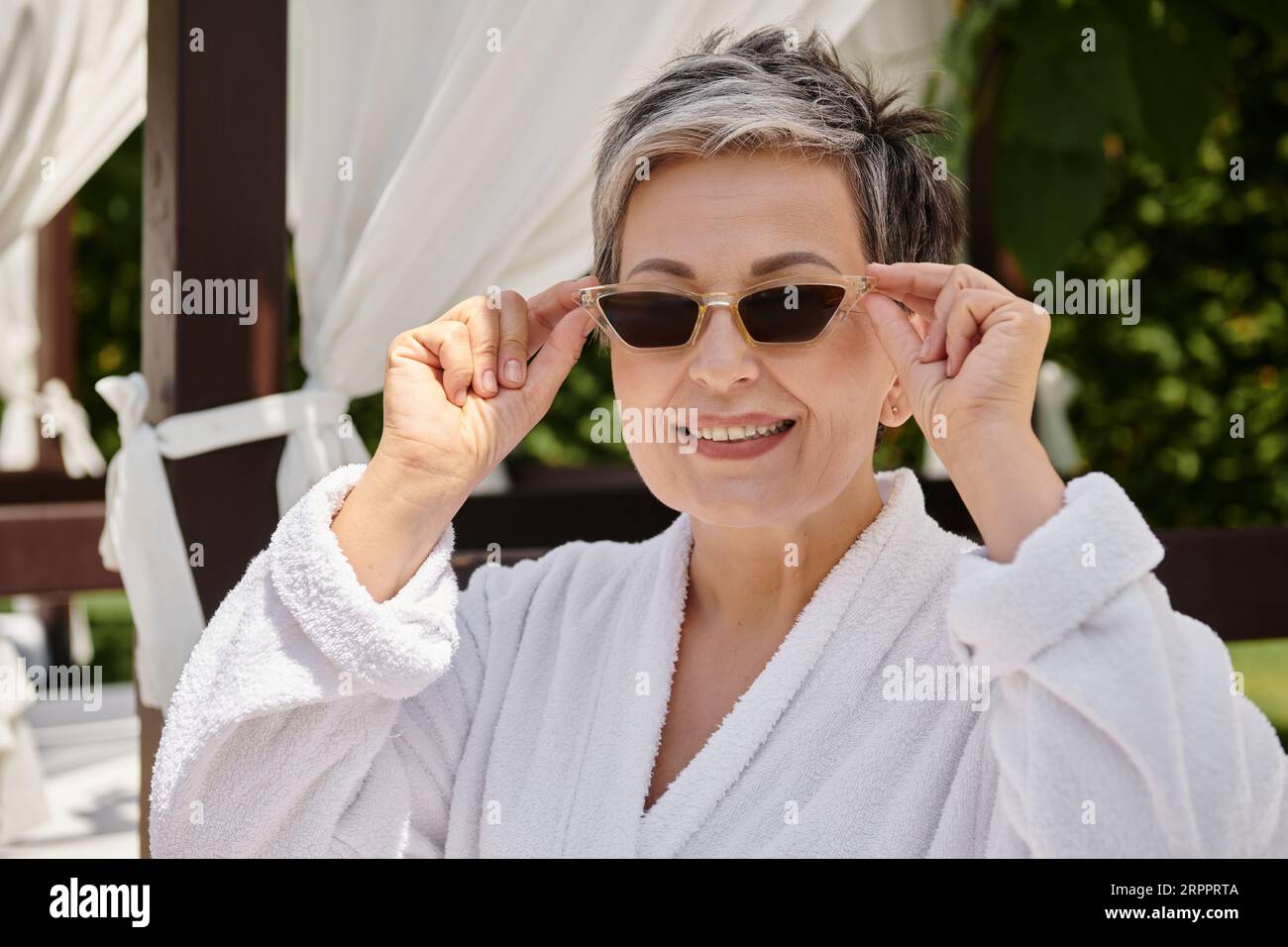 happy middle aged woman wearing sunglasses and looking at camera during ...