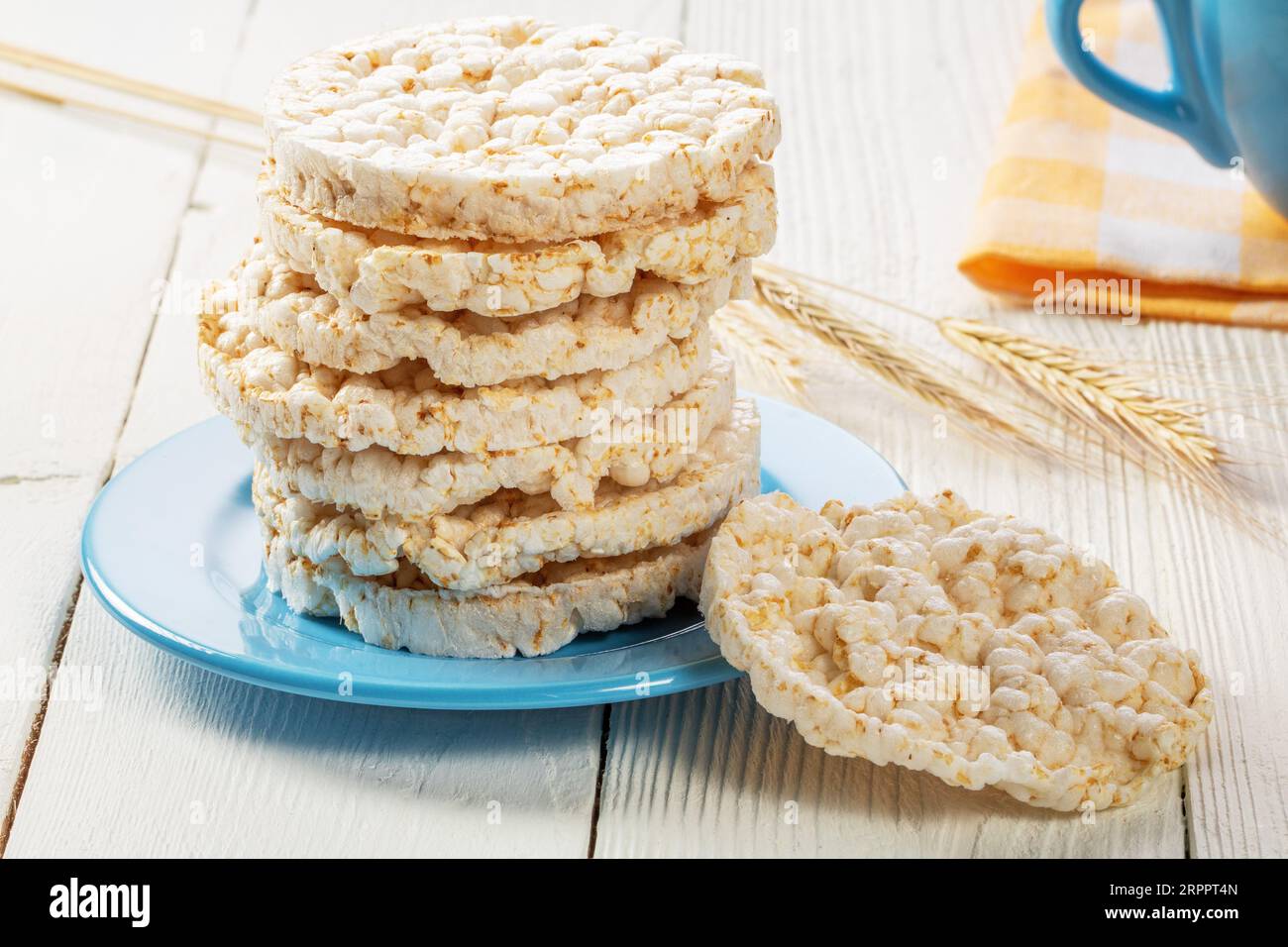 A stack of rice biscuits on a blue saucer and ears of barley on a ...