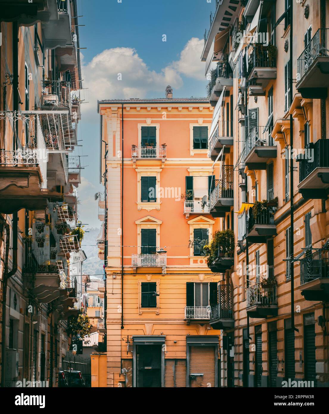 An urban street with yellow colored buildings and metal railings along ...