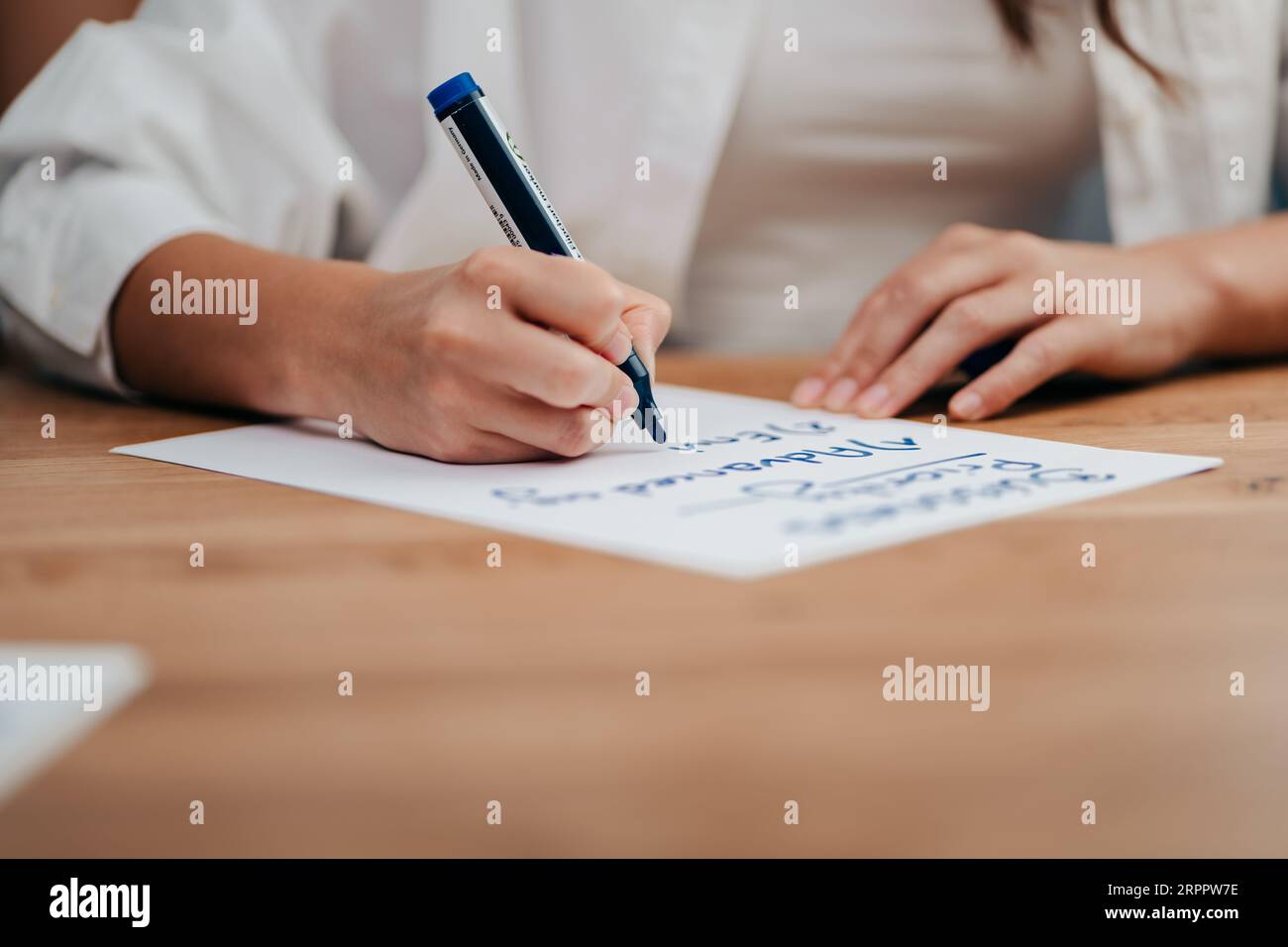 A close-up image of a person writing in a handwritten letter on a piece ...