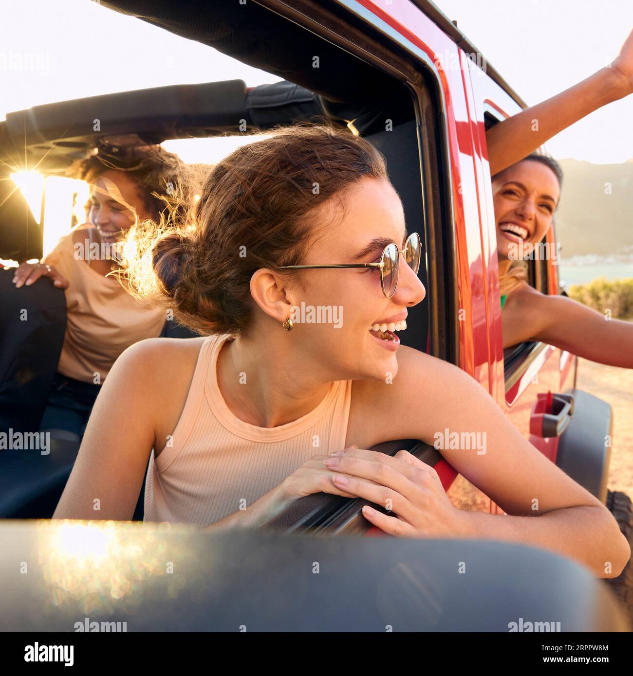 Group Of Laughing Female Friends Having Fun In Open Top Car On Road ...