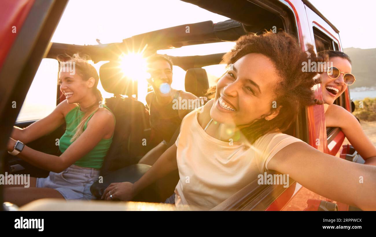Portrait Of Laughing Female Friends Having Fun In Open Top Car On Road ...