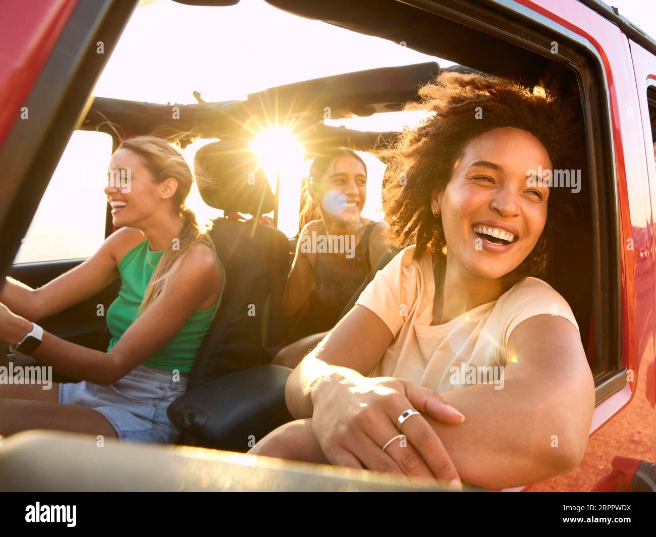 Group Of Laughing Female Friends Having Fun In Open Top Car On Road ...