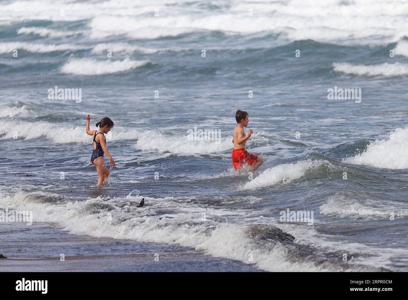 Children running towards waves in the sea at Whitby,North Yorkshire,UK ...