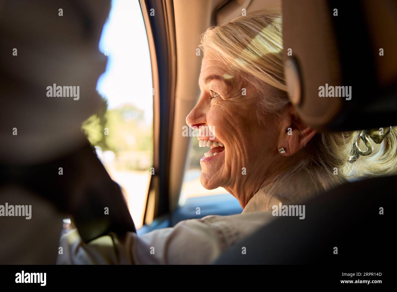 Smiling Senior Female Driver Looking Out Of Car Window Enjoying Day ...
