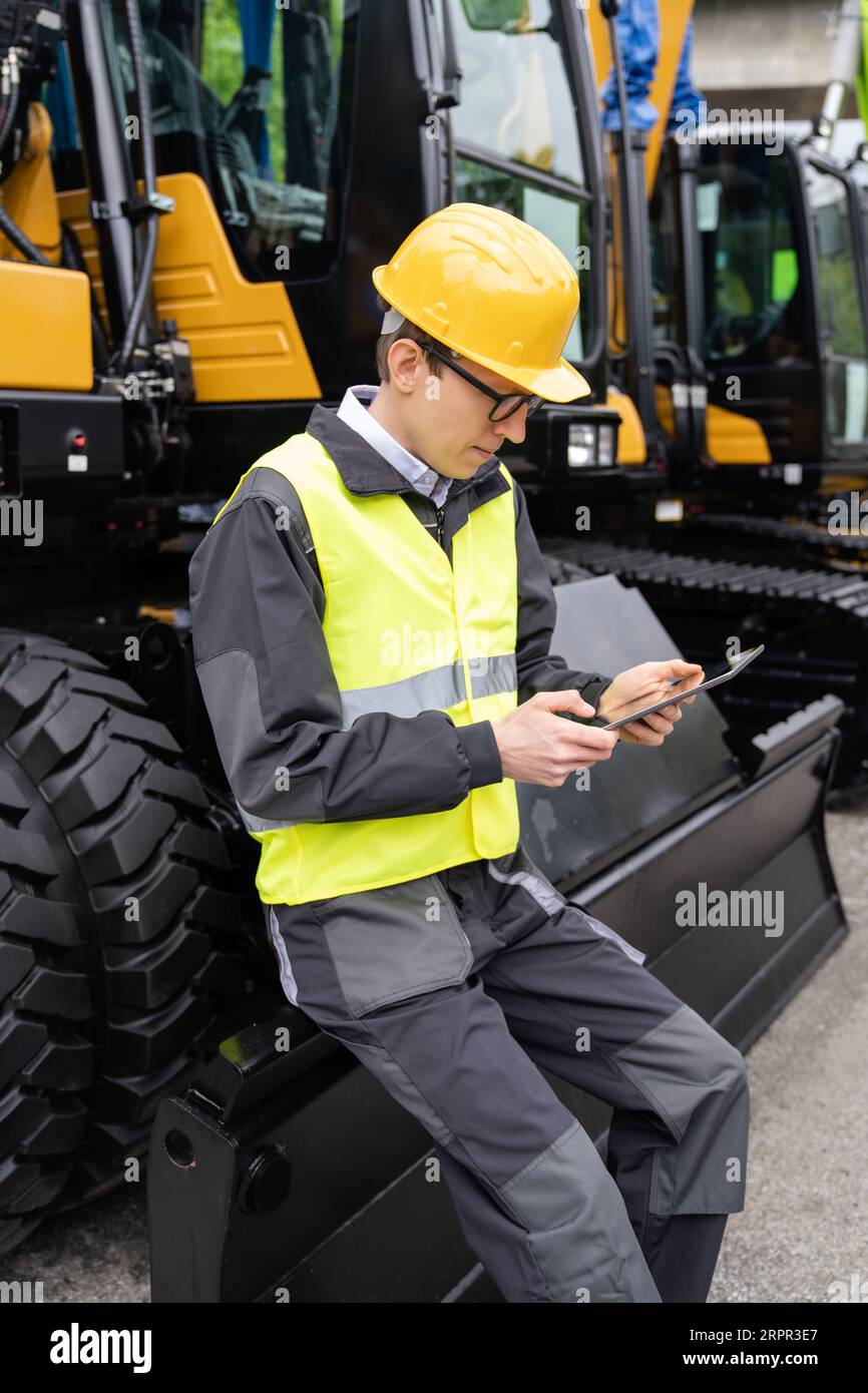 Engineer in a helmet with a digital tablet stands next to construction ...