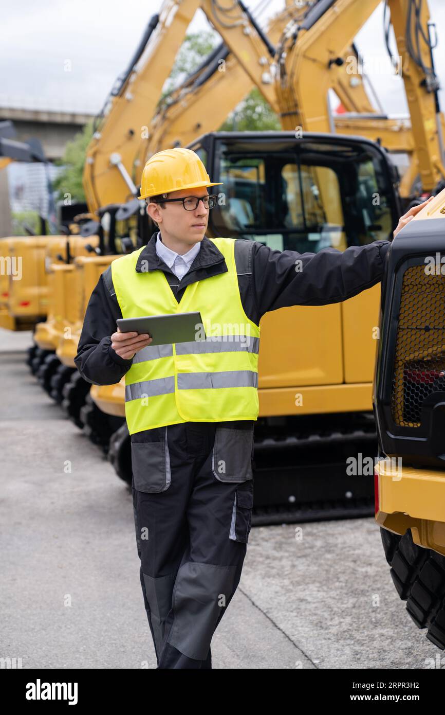 Engineer in a helmet with a digital tablet stands next to construction ...