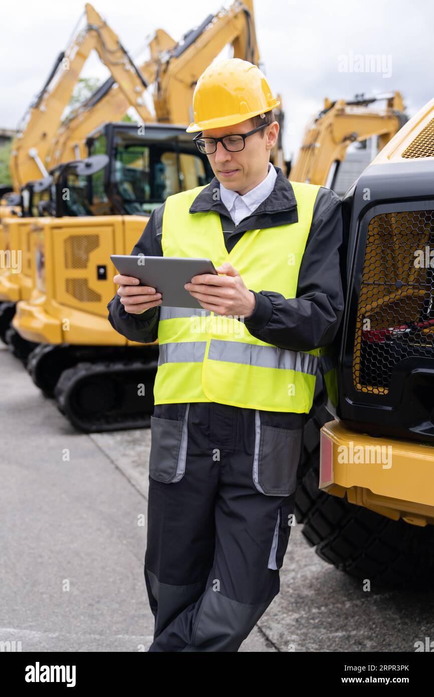 Engineer in a helmet with a digital tablet stands next to construction ...