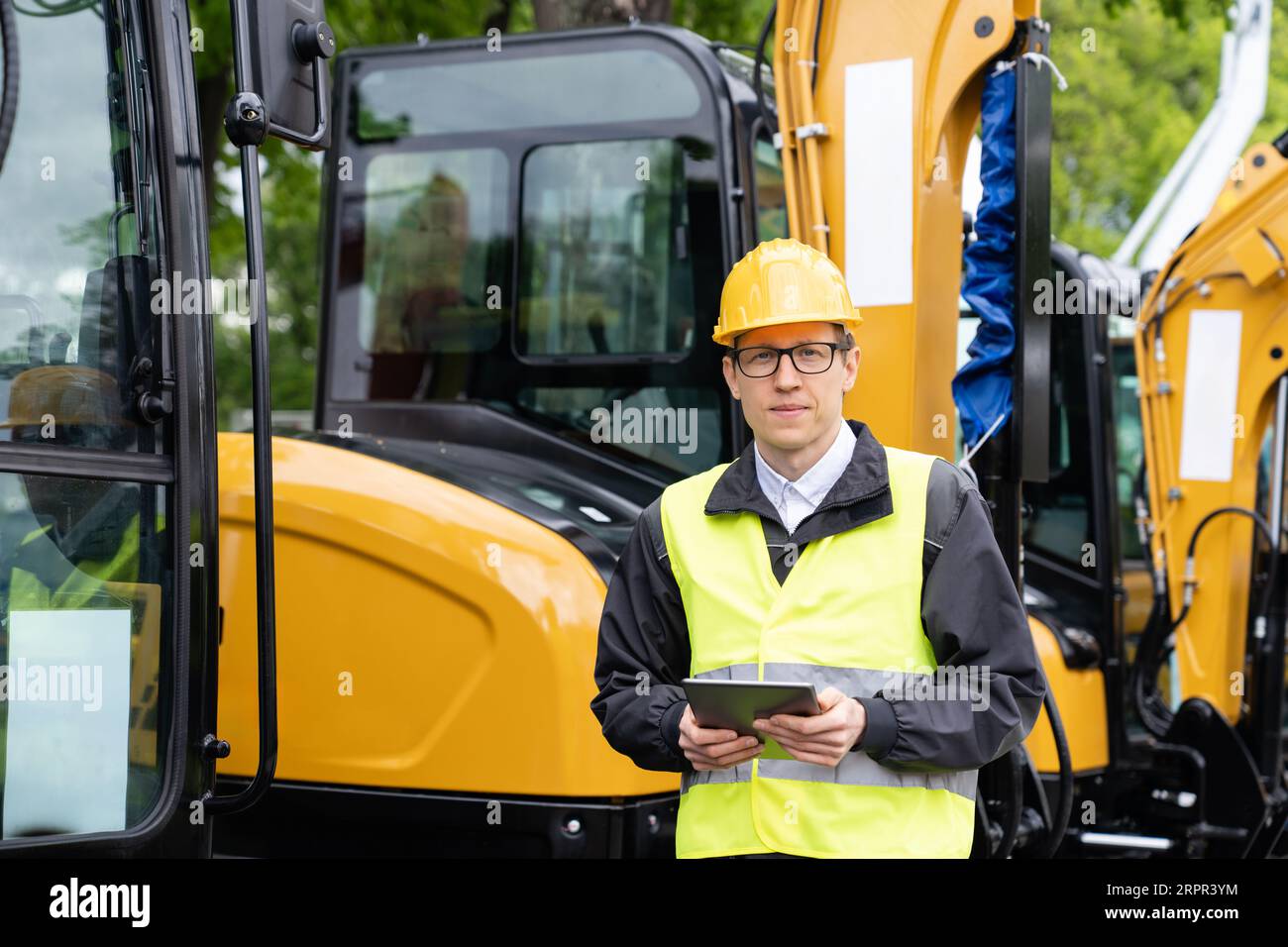 Engineer in a helmet with a digital tablet stands next to construction ...