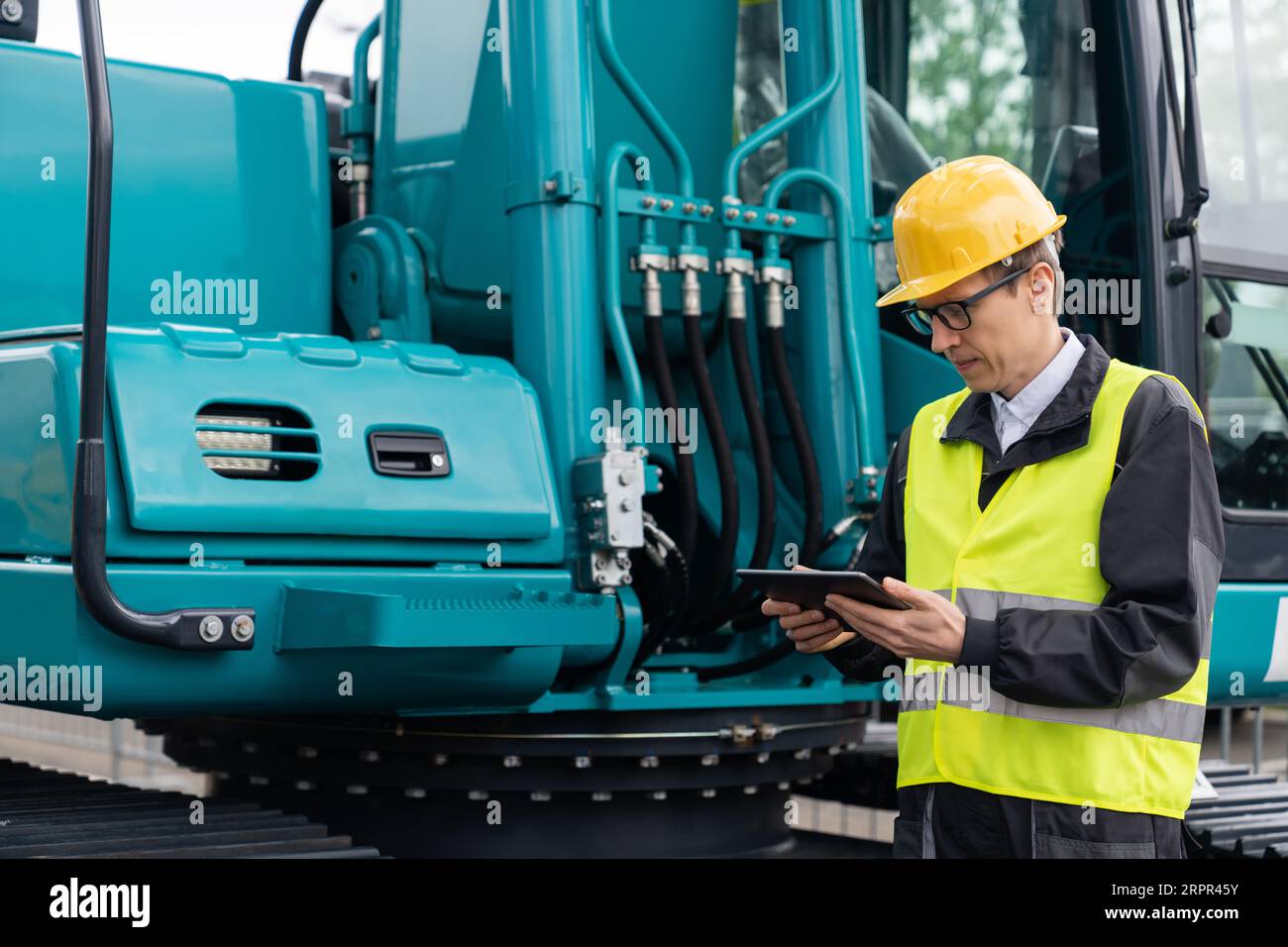 Engineer in a helmet with a digital tablet stands next to construction ...