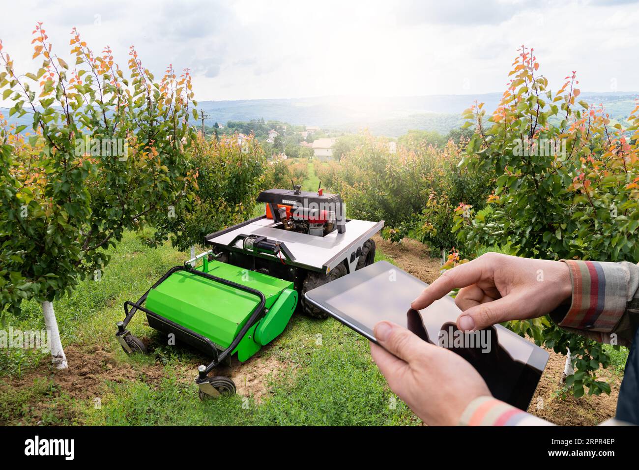 Farmer with digital tablet controls autonomous lawnmower Stock Photo ...